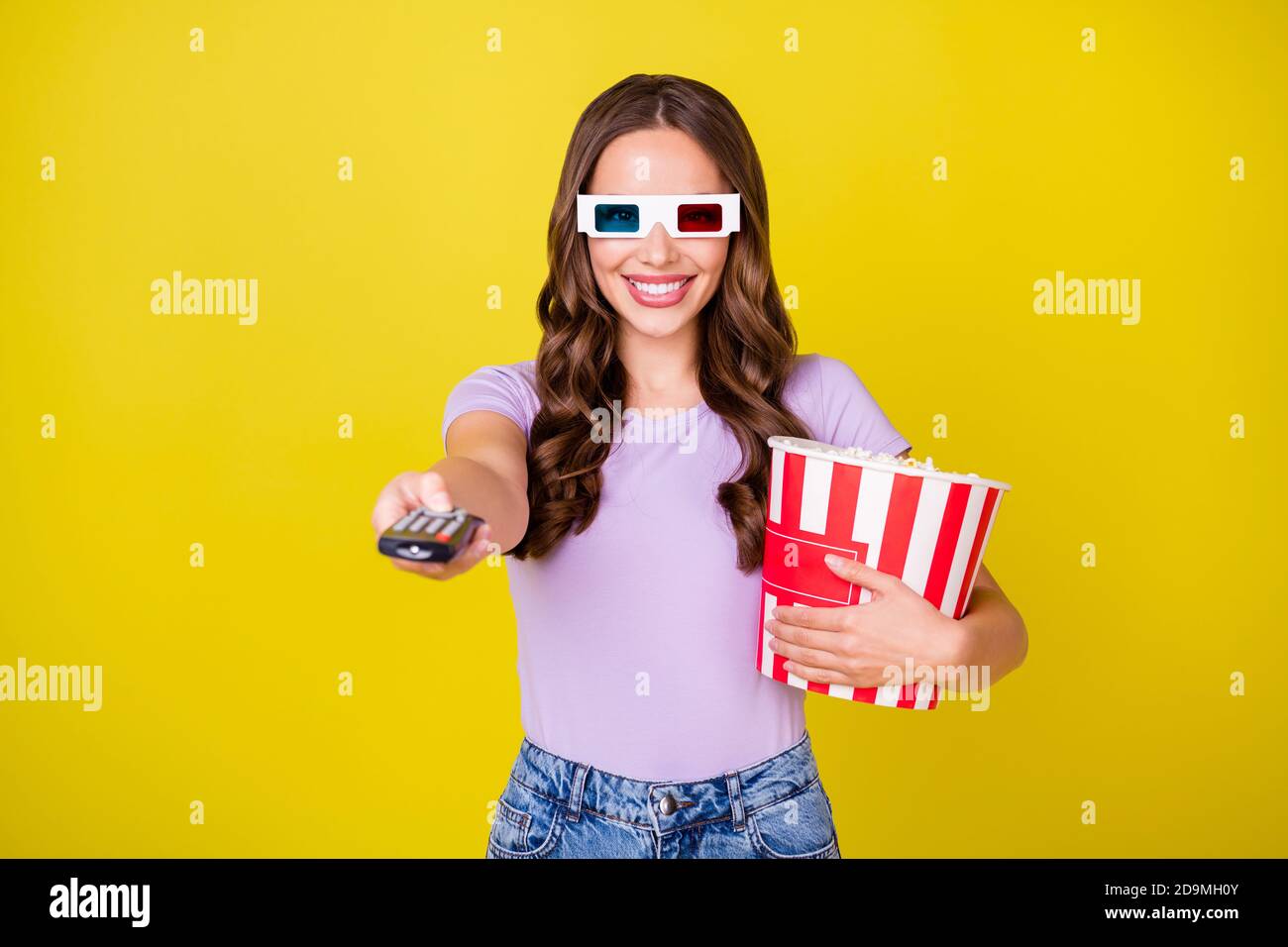 Portrait of lovely cheerful wavy-haired girl eating corn watching tv ...