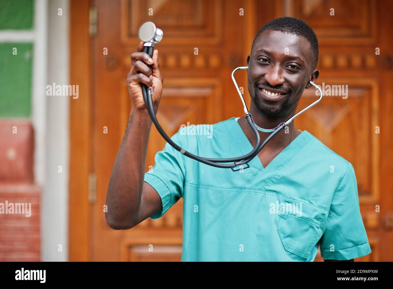 Portrait of African male doctor with stethoscope wearing green coat ...