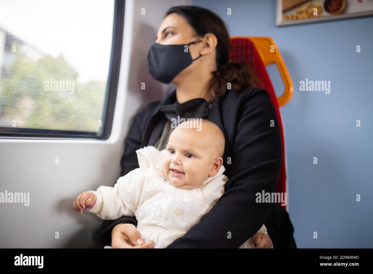 Woman looking through the window of a bus and holding her smiling baby ...