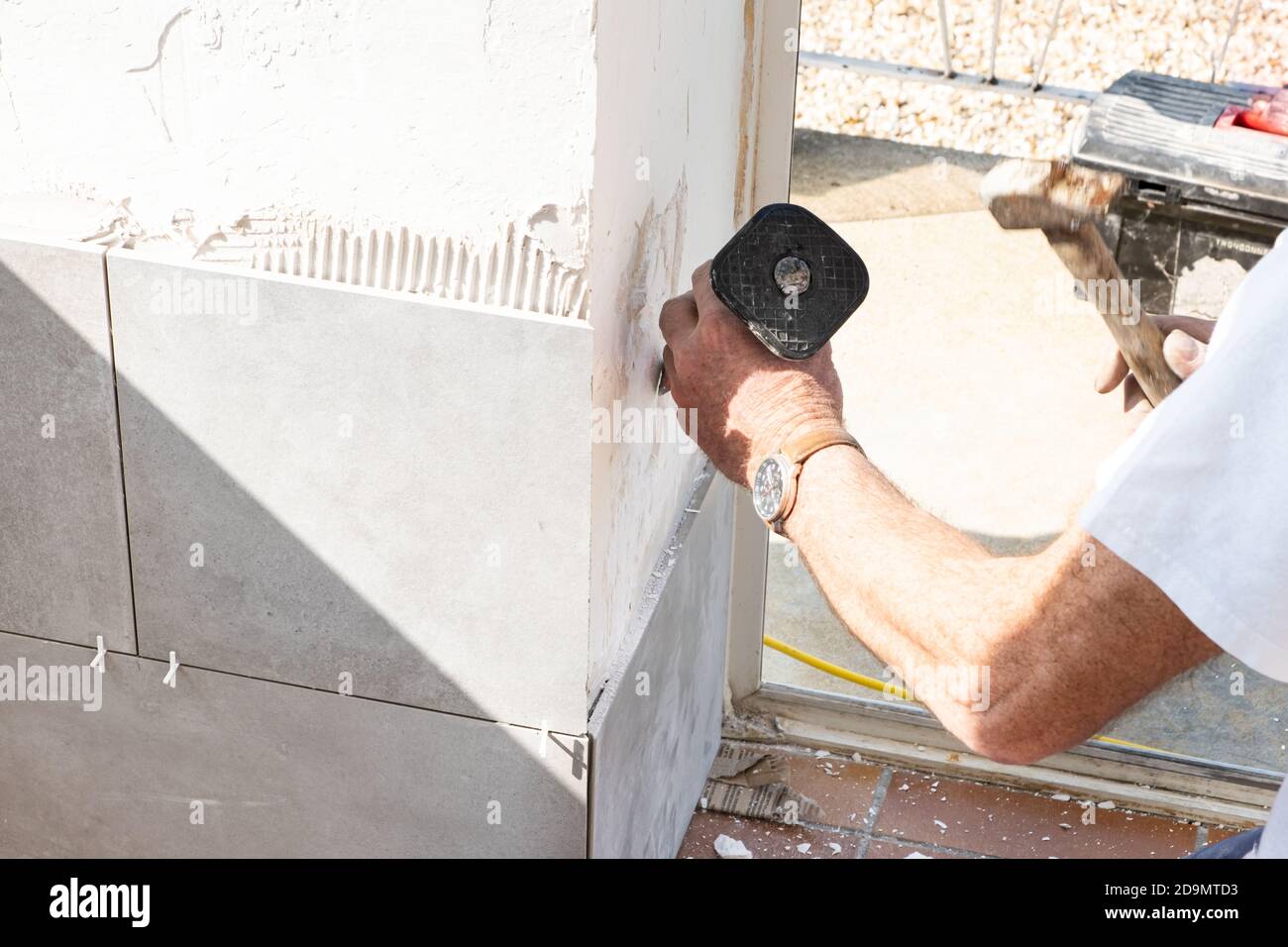 the mason prepares the wall with a chisel before laying a ceramic tile ...
