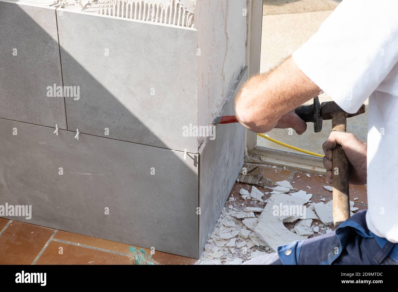 the mason prepares the wall with a chisel before laying a ceramic tile ...