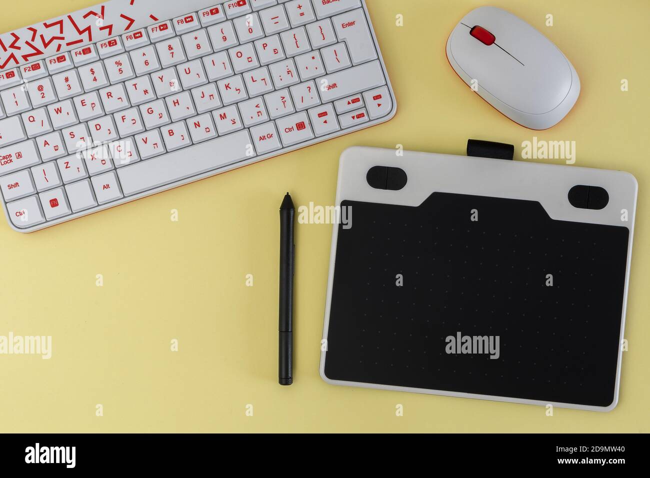 Top view of a graphic tablet, keyboard, and mouse on yellow background ...