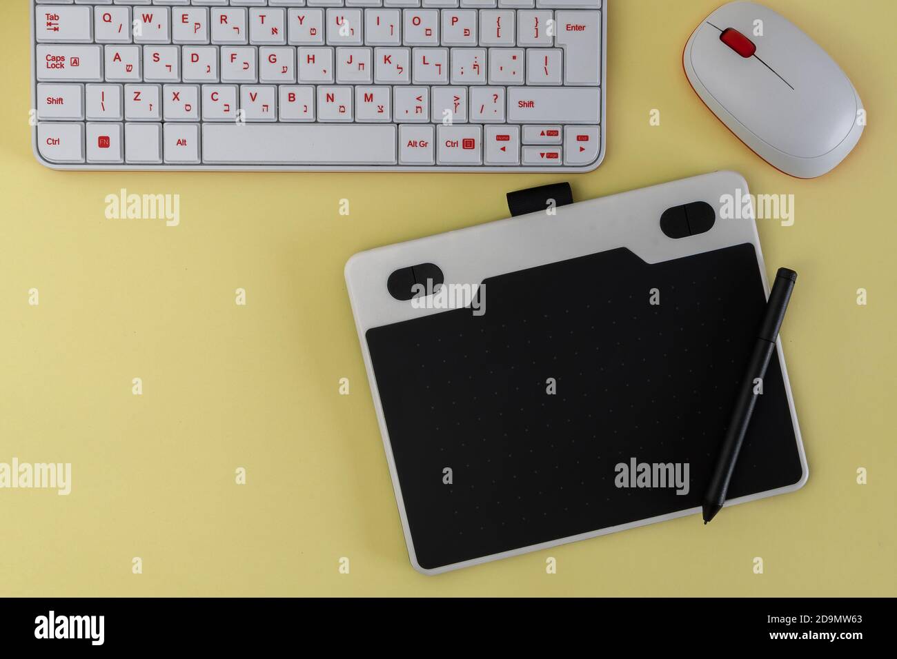 Top view of a graphic tablet, keyboard, and mouse on yellow background ...