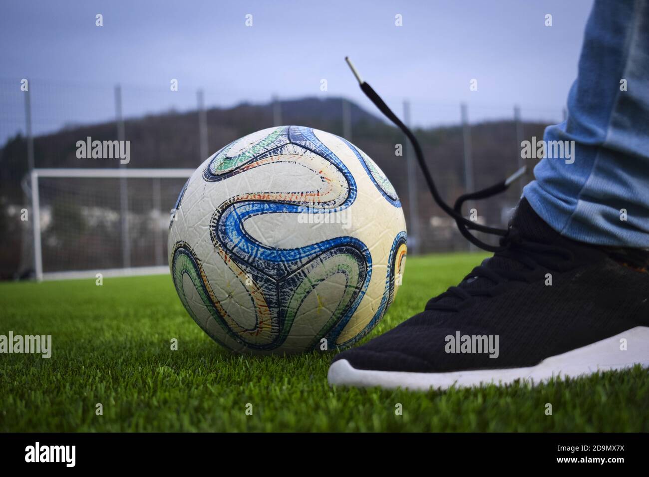 Selective focus shot of a ball with a male foot on a football stadium ...