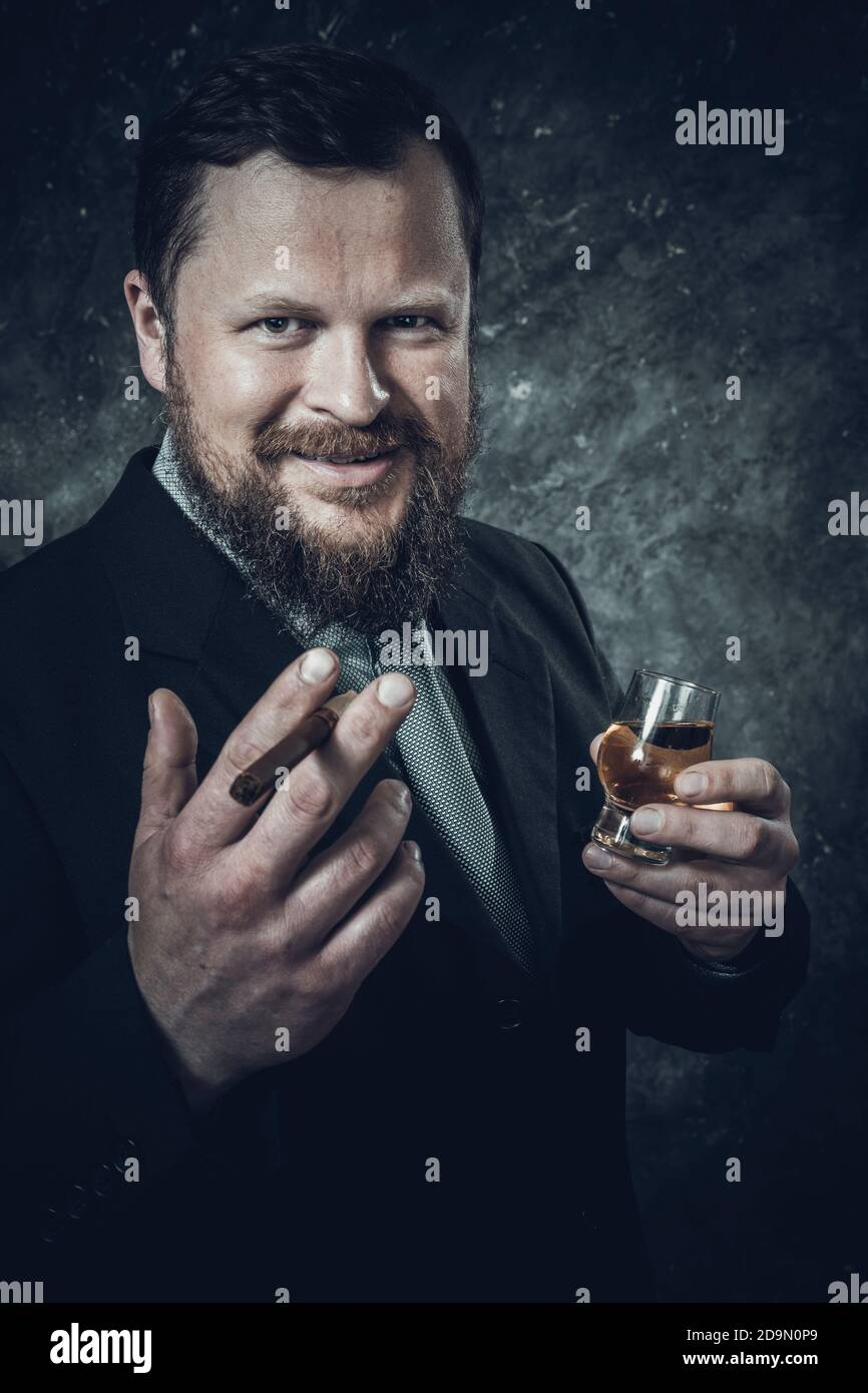 Solid confident bearded man in suit with glass of whisky and cigar ...