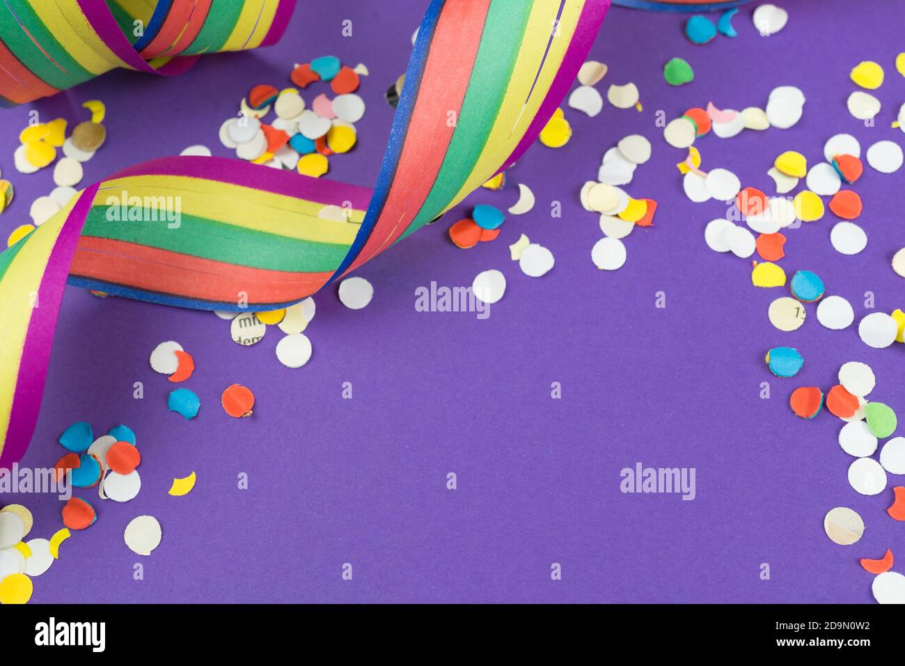 Streamers and confetti on a violet background Stock Photo - Alamy