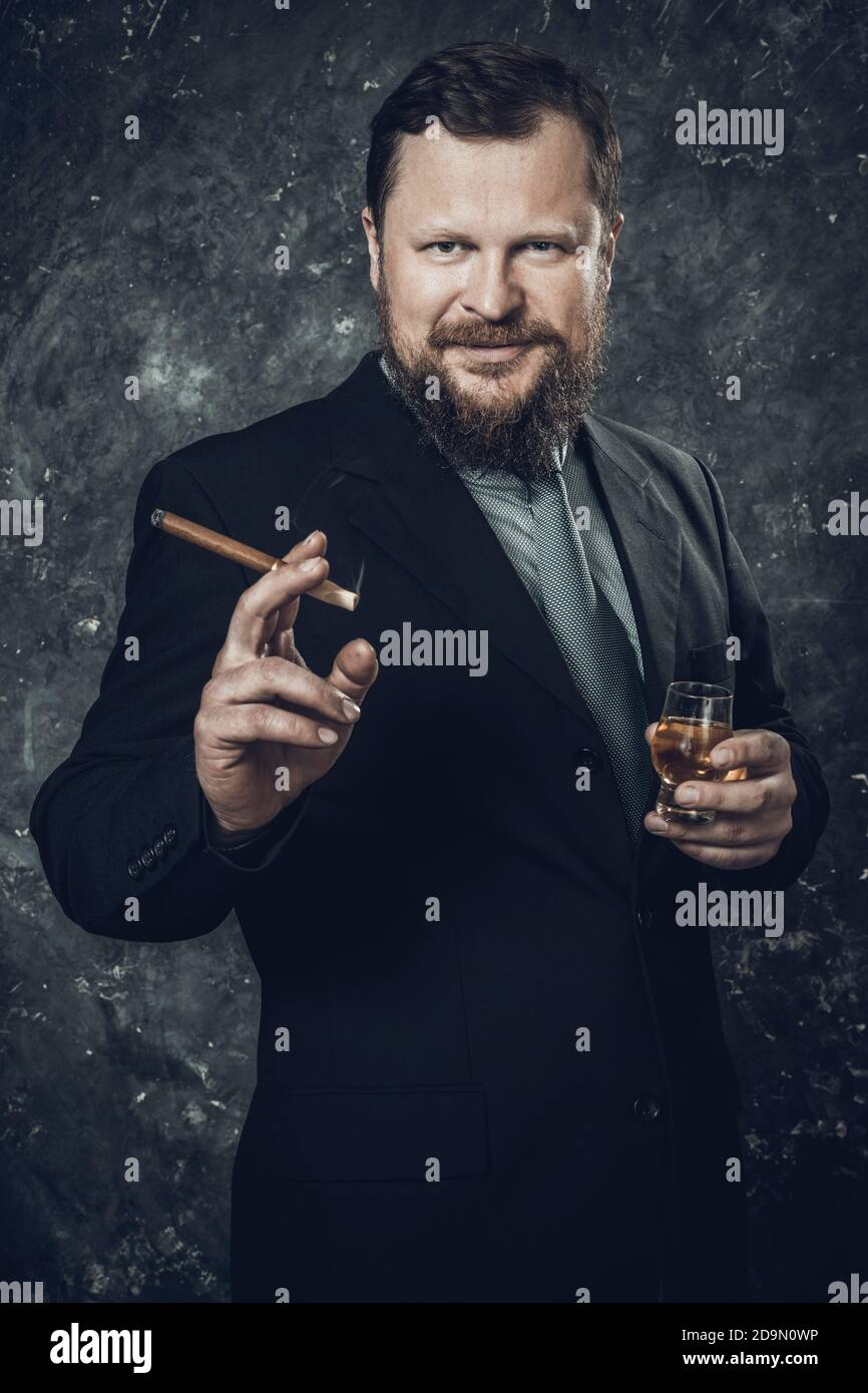 Solid confident bearded man in suit with glass of whisky and cigar ...