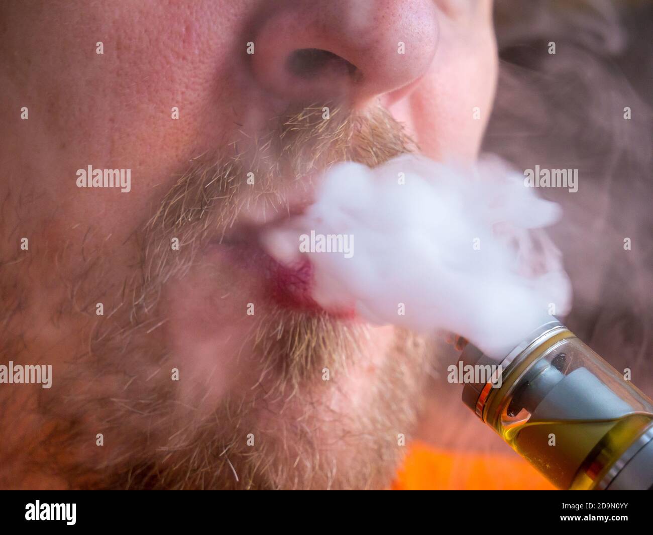 Close-up of mouth with mustache using electronic cigarette and exhaling ...