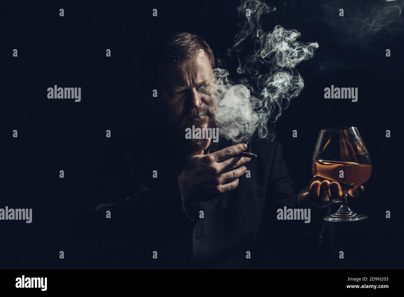 Solid confident bearded man in suit with glass of whisky and cigar with ...