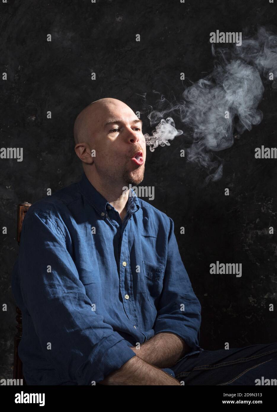 Matured bold man smoking, portrait on black background Stock Photo - Alamy