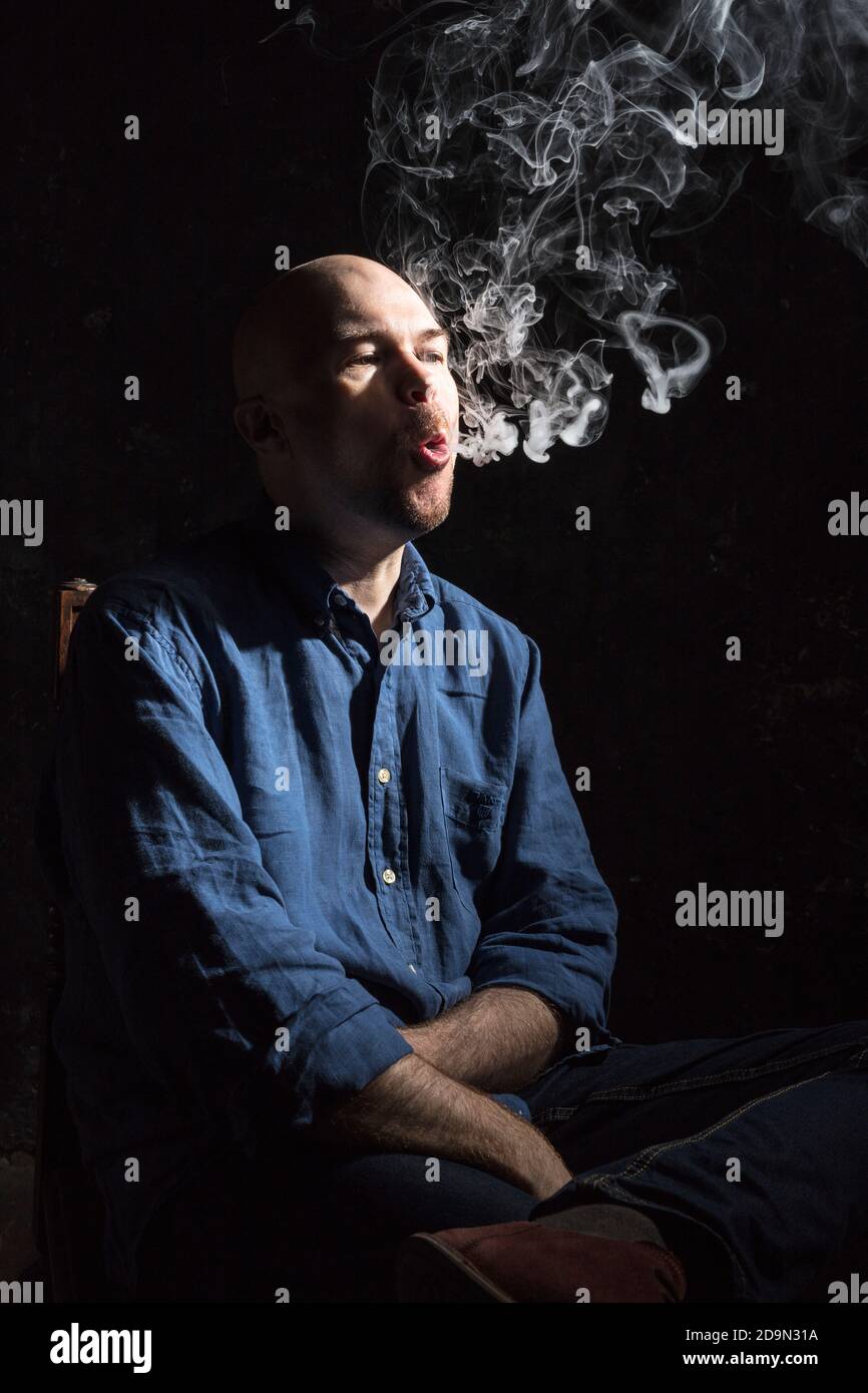 Matured bold man smoking, portrait on black background Stock Photo - Alamy
