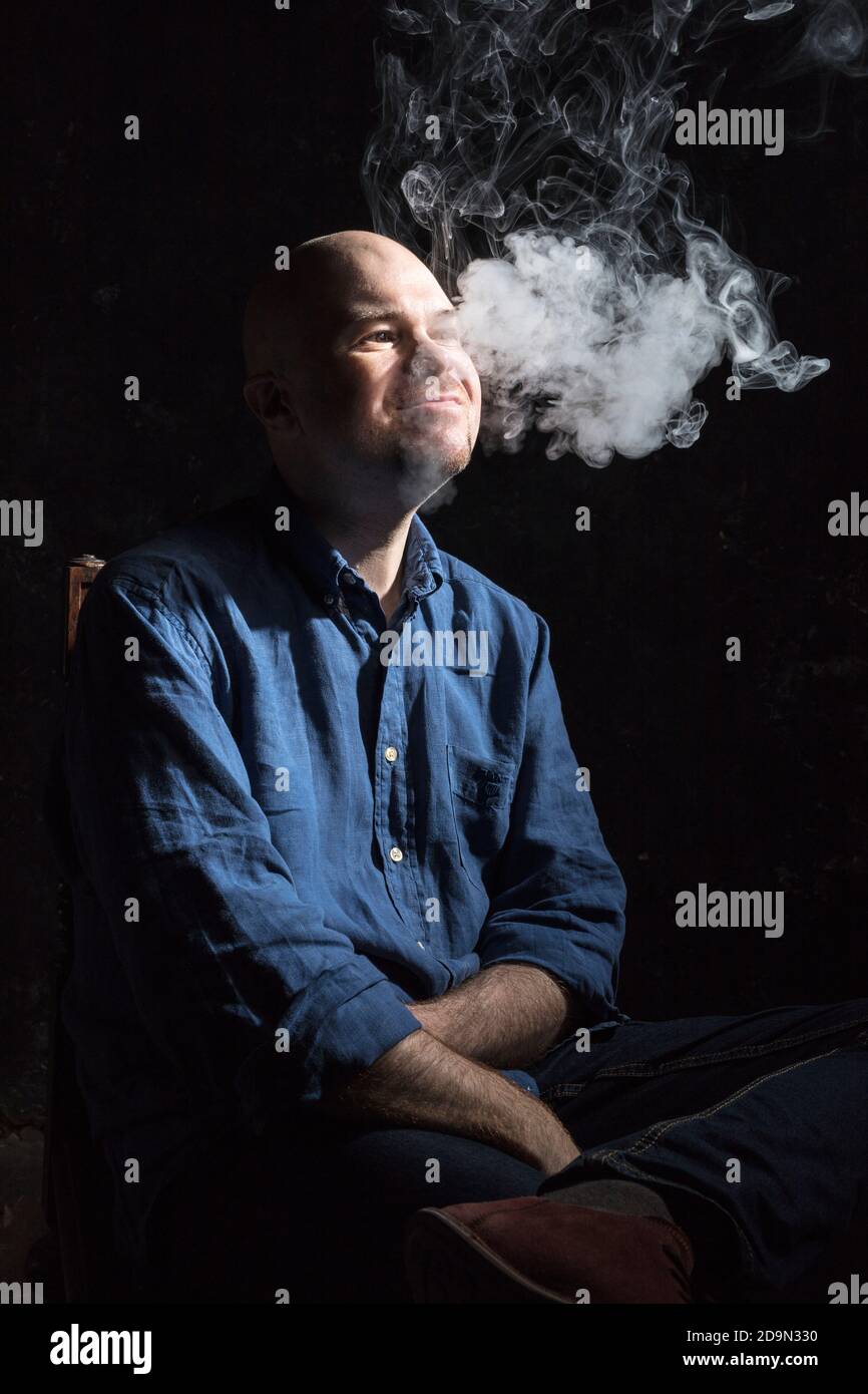 Matured bold man smoking, portrait on black background Stock Photo - Alamy