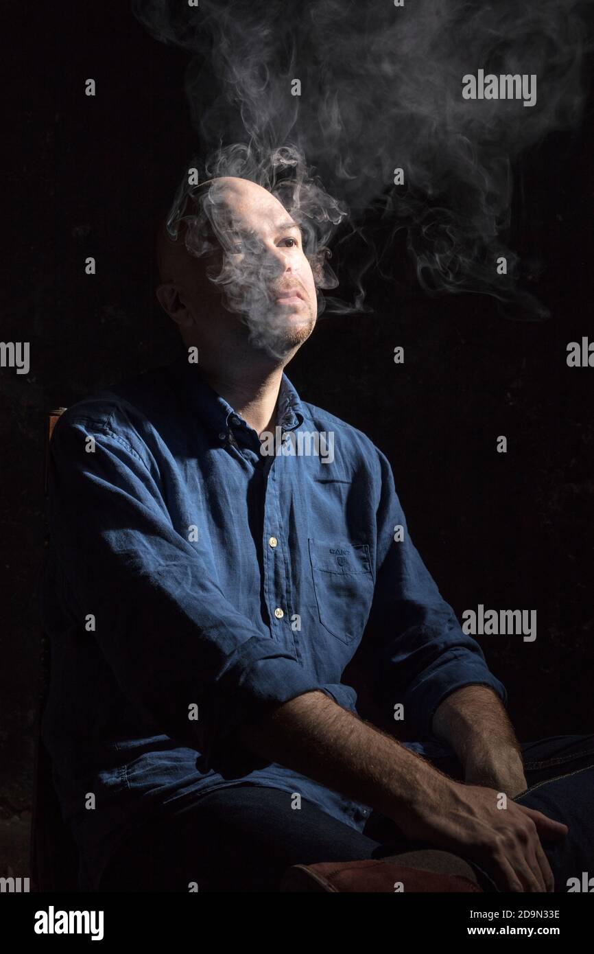 Matured bold man smoking, portrait on black background Stock Photo - Alamy