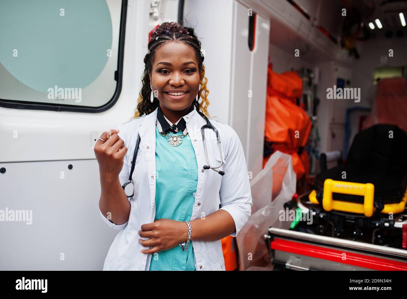 African american female paramedic standing in front of ambulance car ...