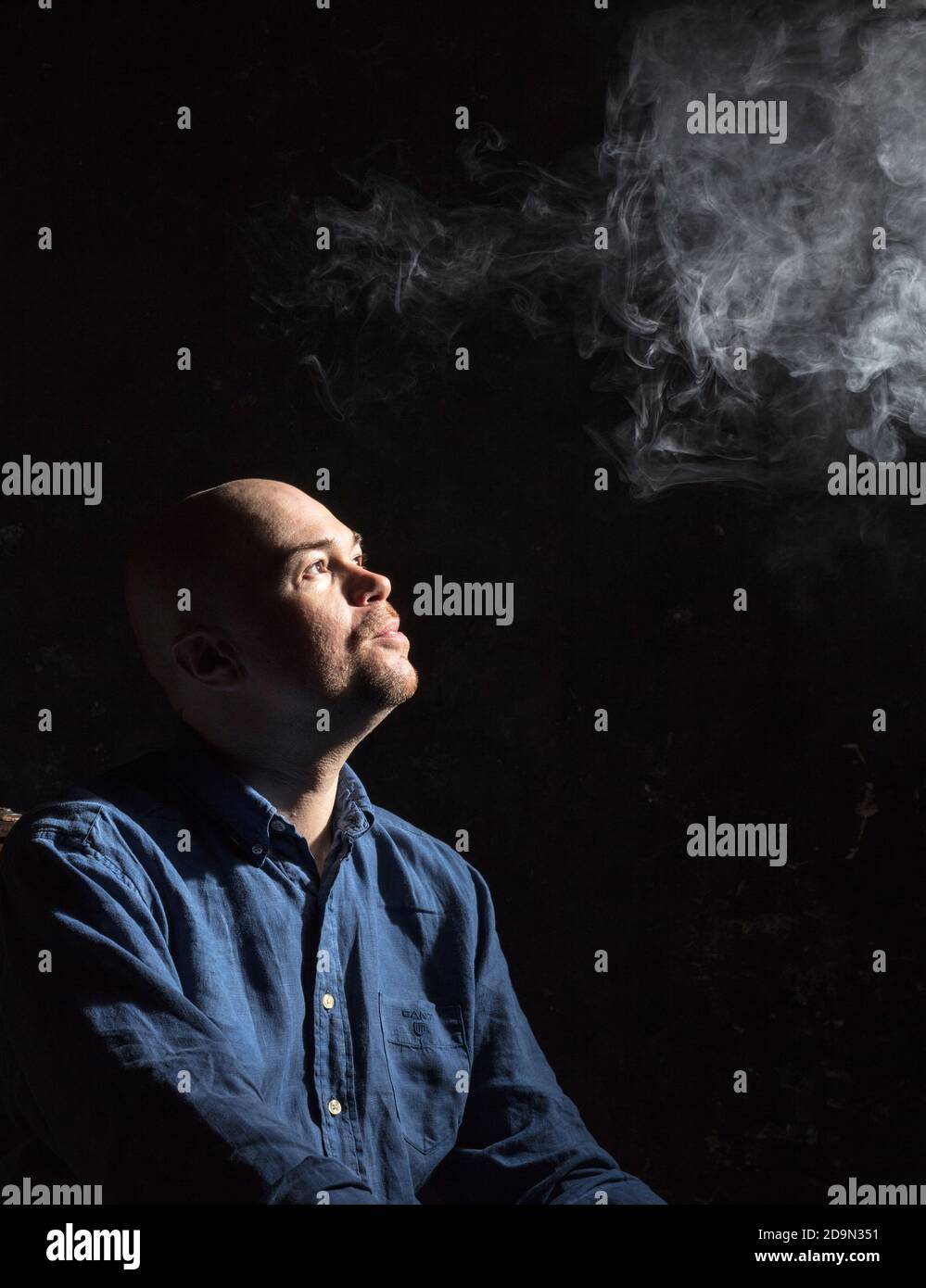 Matured bold man smoking, portrait on black background Stock Photo - Alamy