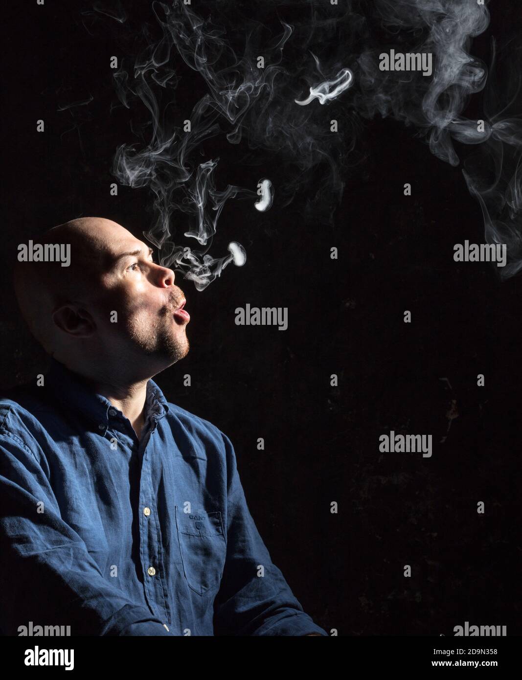 Matured bold man smoking, portrait on black background Stock Photo - Alamy