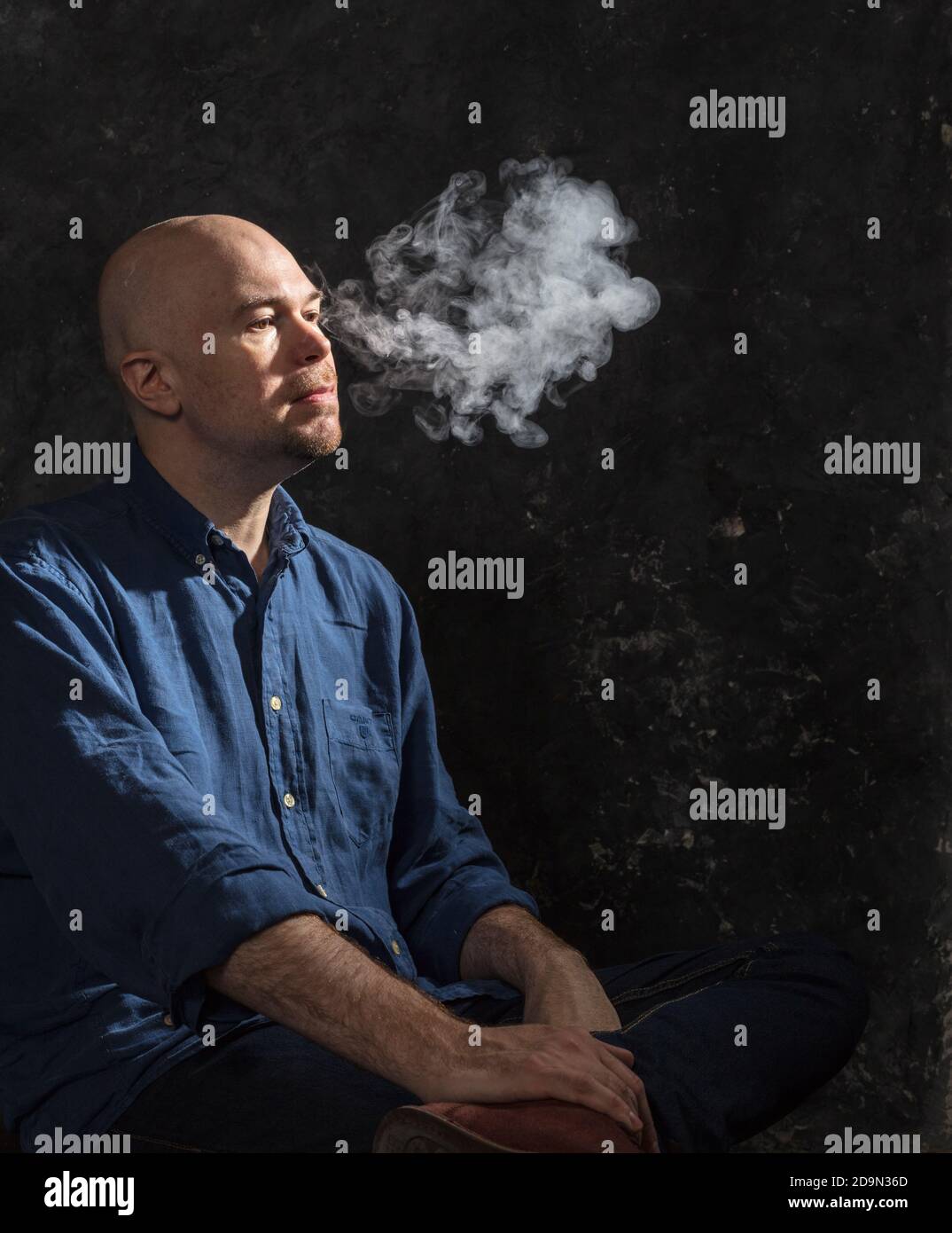 Matured bold man smoking, portrait on black background Stock Photo - Alamy