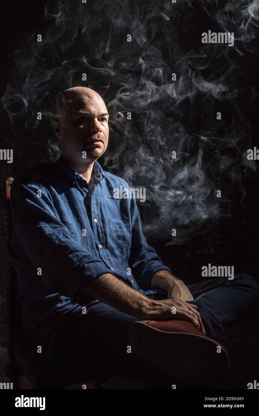 Matured bold man smoking, portrait on black background Stock Photo - Alamy