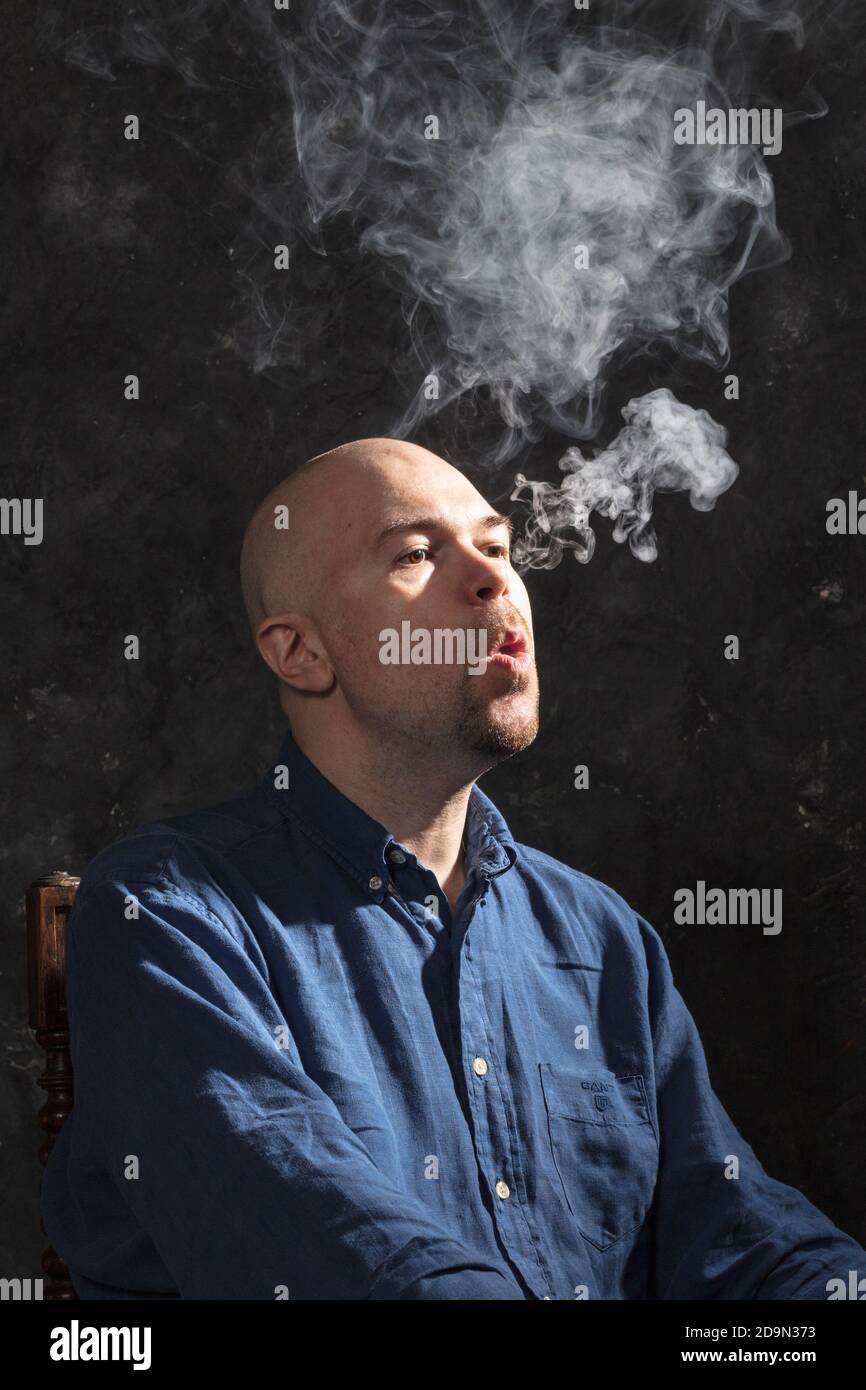 Matured bold man smoking, portrait on black background Stock Photo - Alamy
