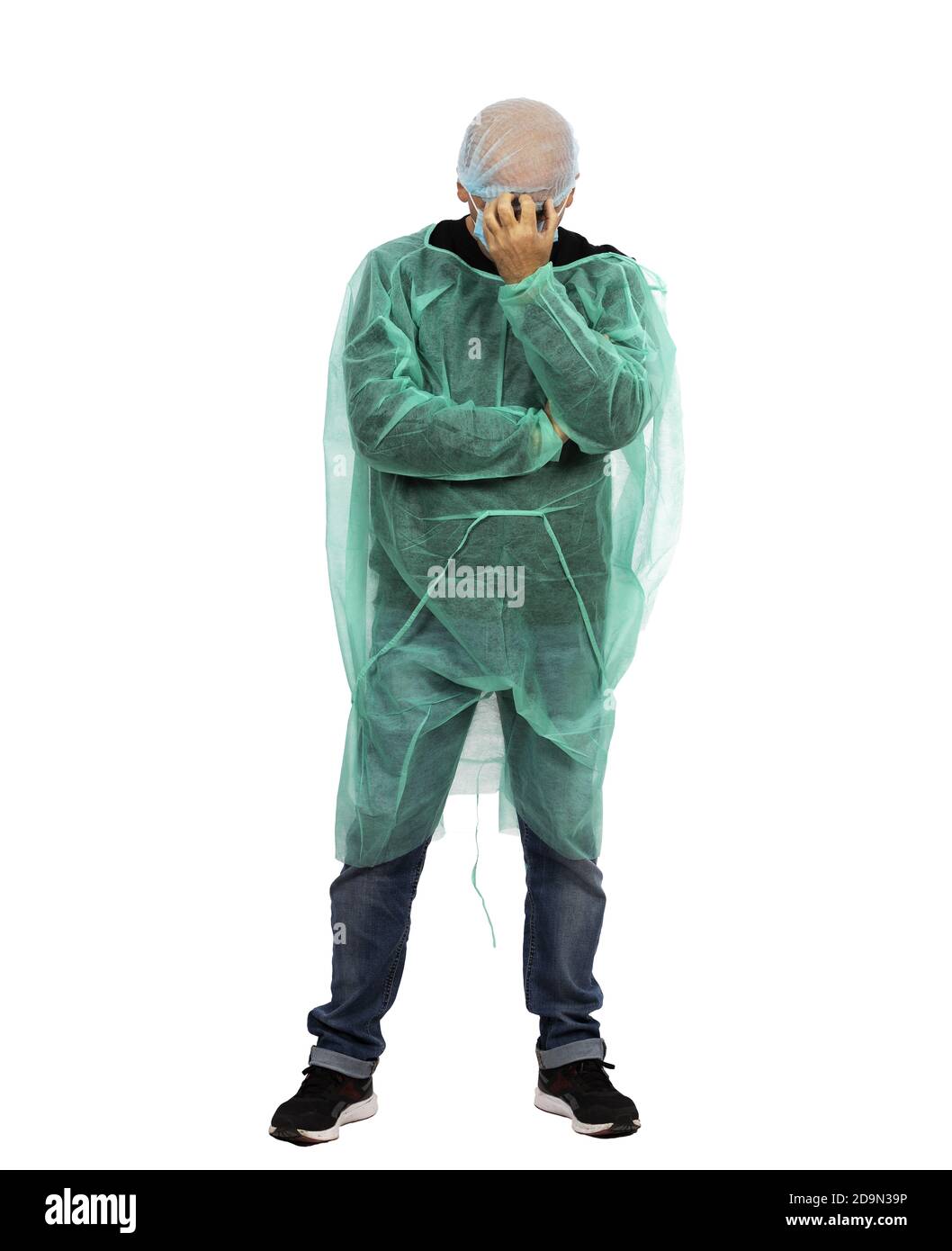 Man wearing a face mask, surgical gown, cap and shoe covers holding his ...