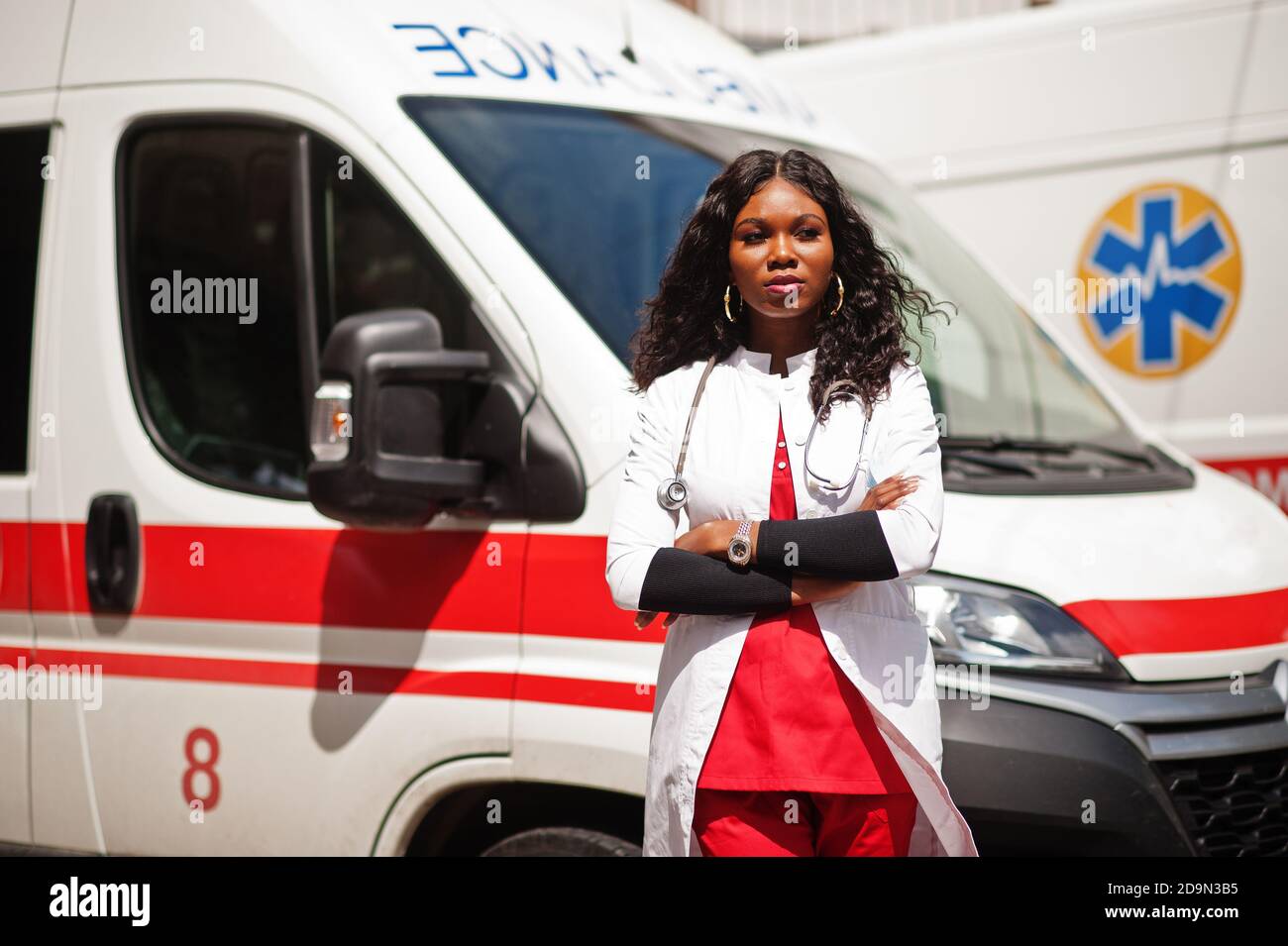 African american female paramedic standing in front of ambulance car ...