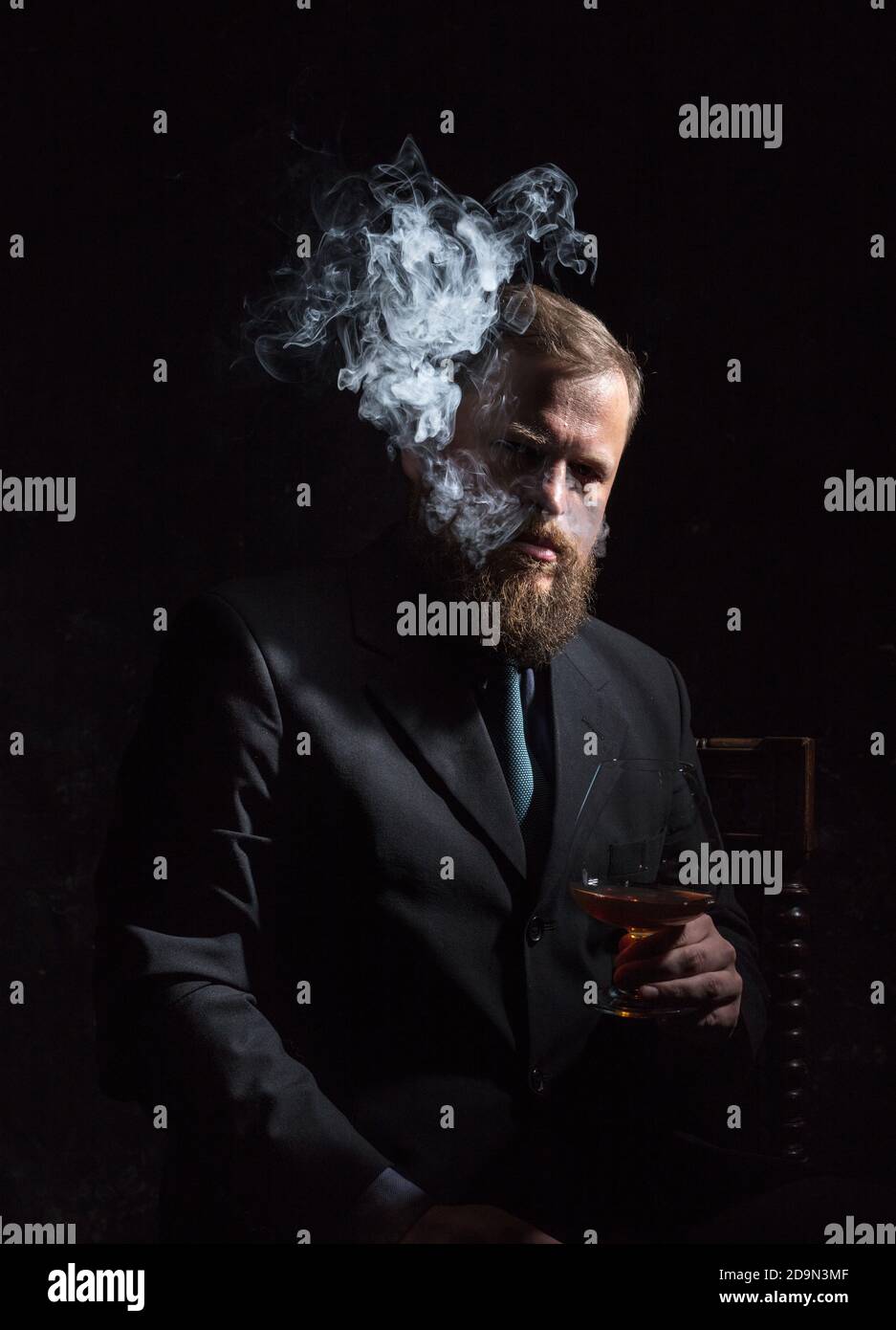 Solid confident bearded man in suit with glass of whisky and fume ...