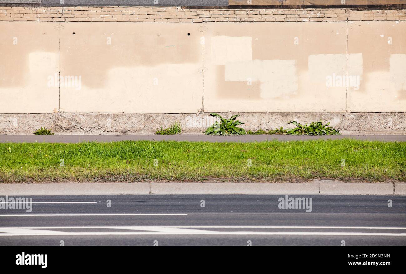 Urban road roadside with green grass and concrete wall, background ...