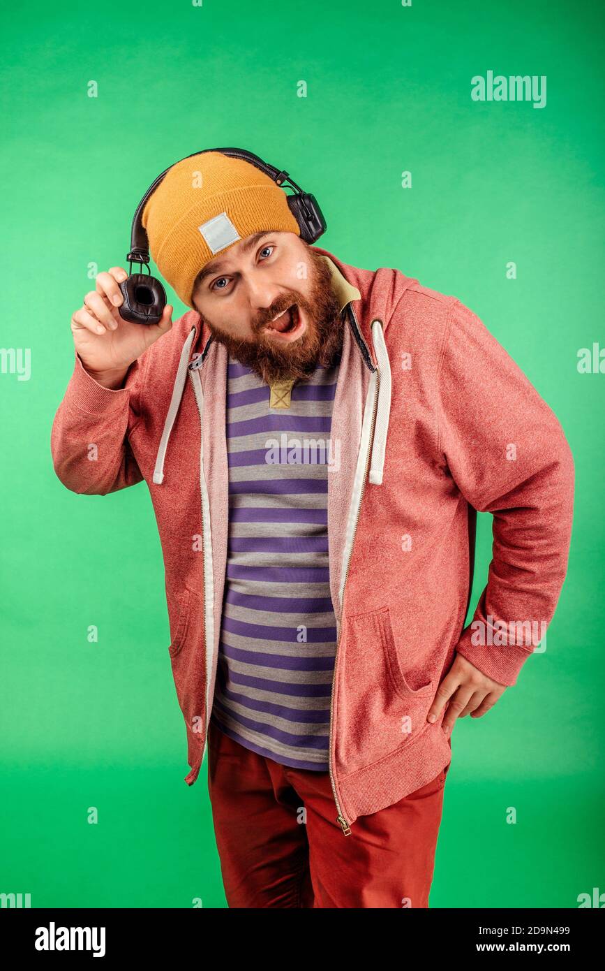 close-up of a man taking off headphones on green studio background ...