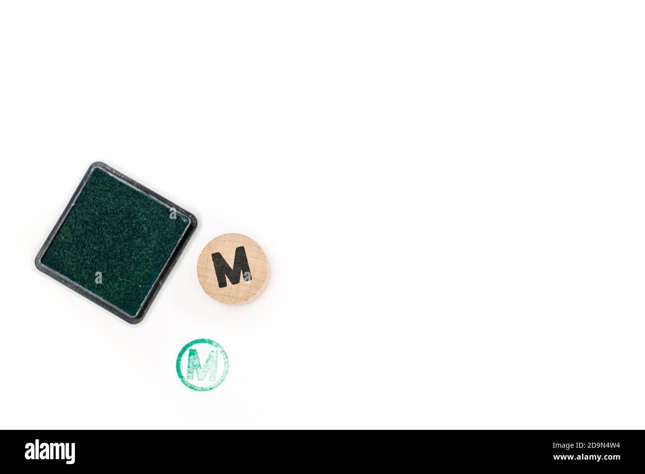 round wooden stamp letter M stamped and pad with green ink Stock Photo ...