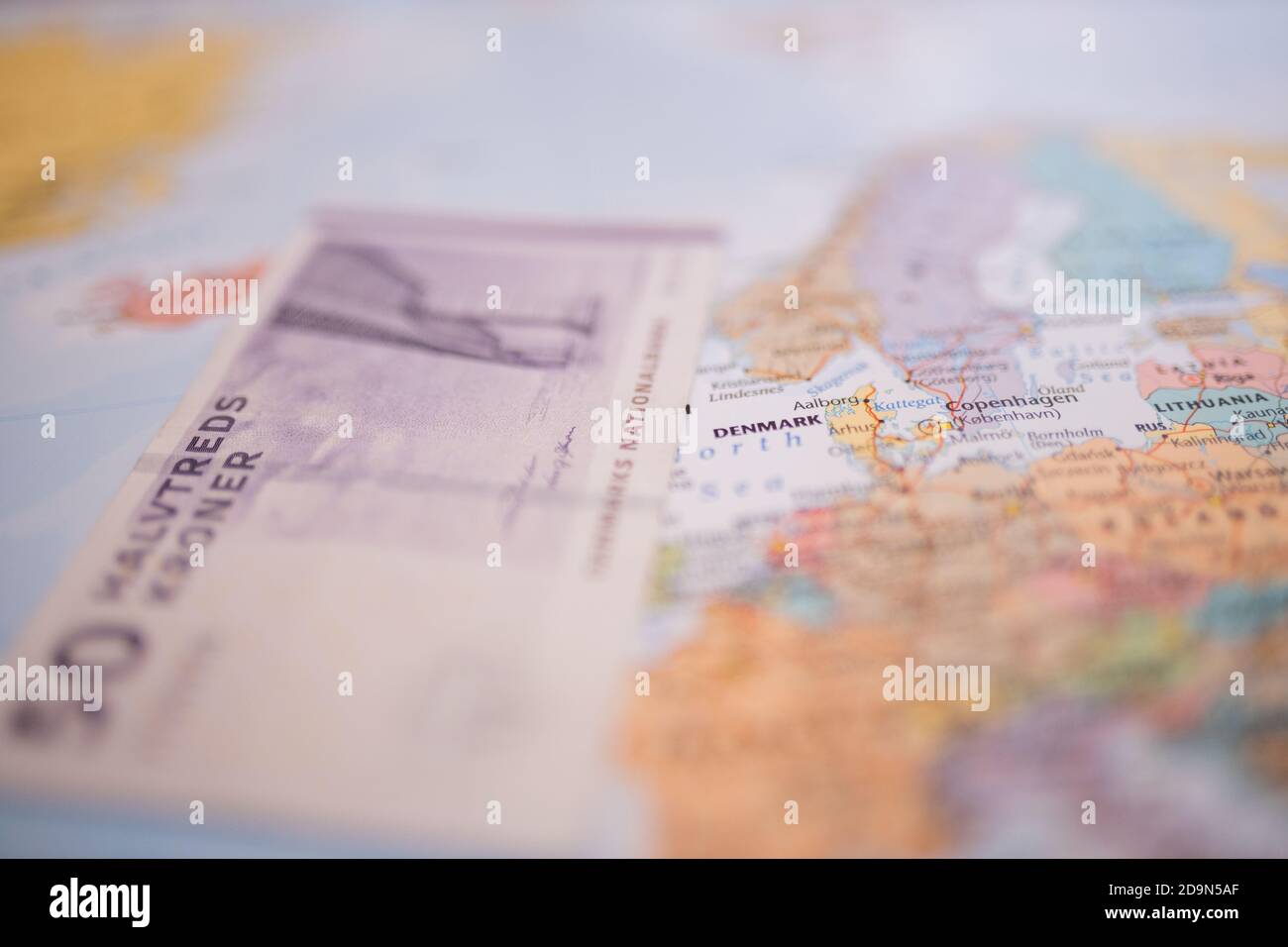 Fifty Danish kroner bill next to Denmark on a colorful and blurry map ...