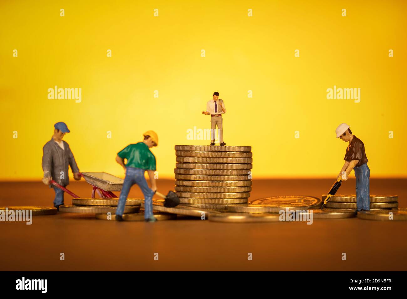 Construction worker figures with their boss on a stack of coins against ...