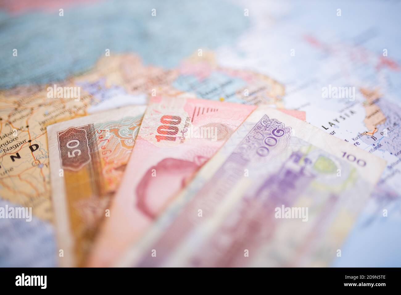 50 kyat bill, 100 baht bill, and a 100 riels bill on a map of Southeast ...