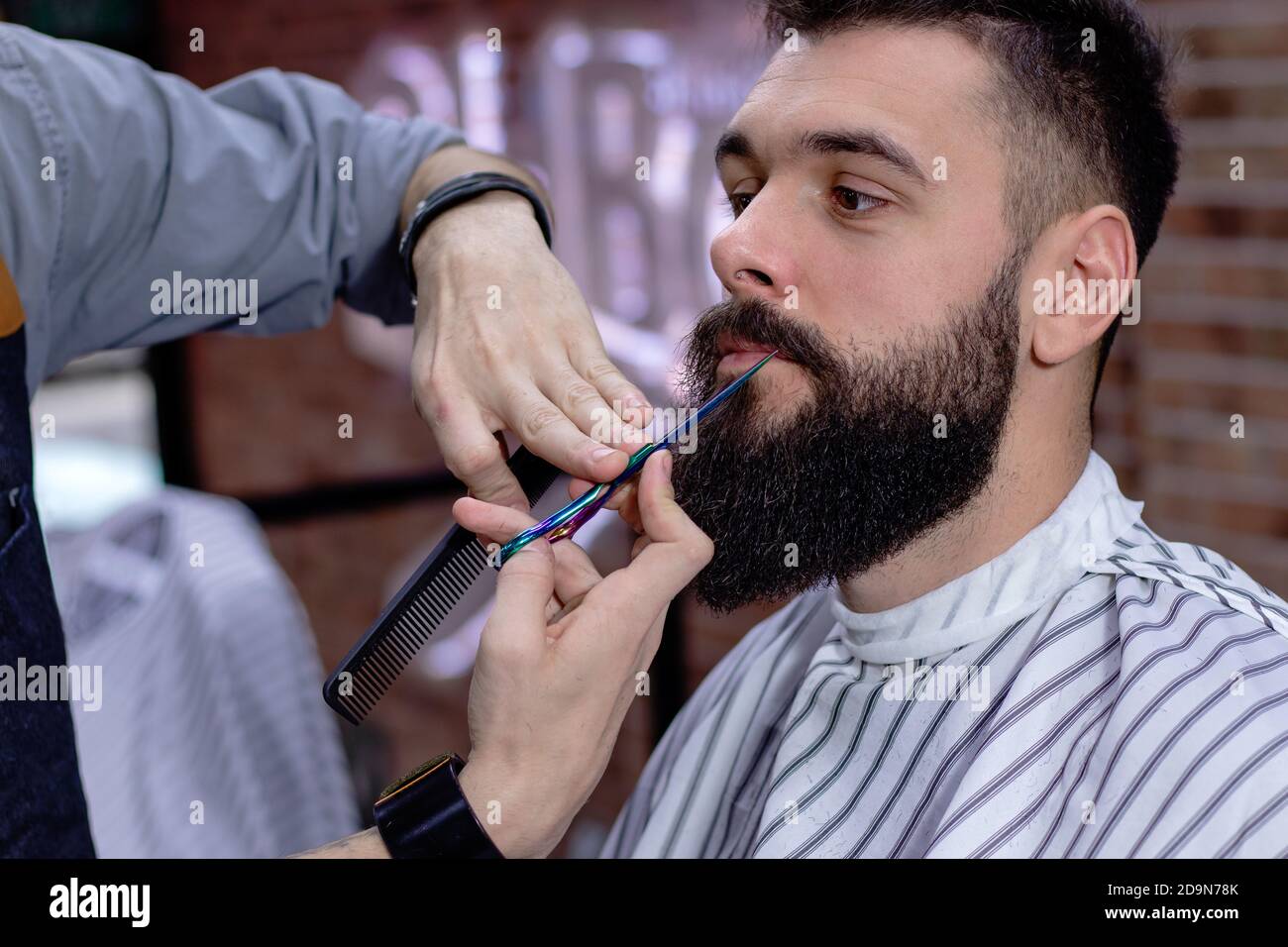 Beard styling and cutting with scissors. Young bearded hipster man ...