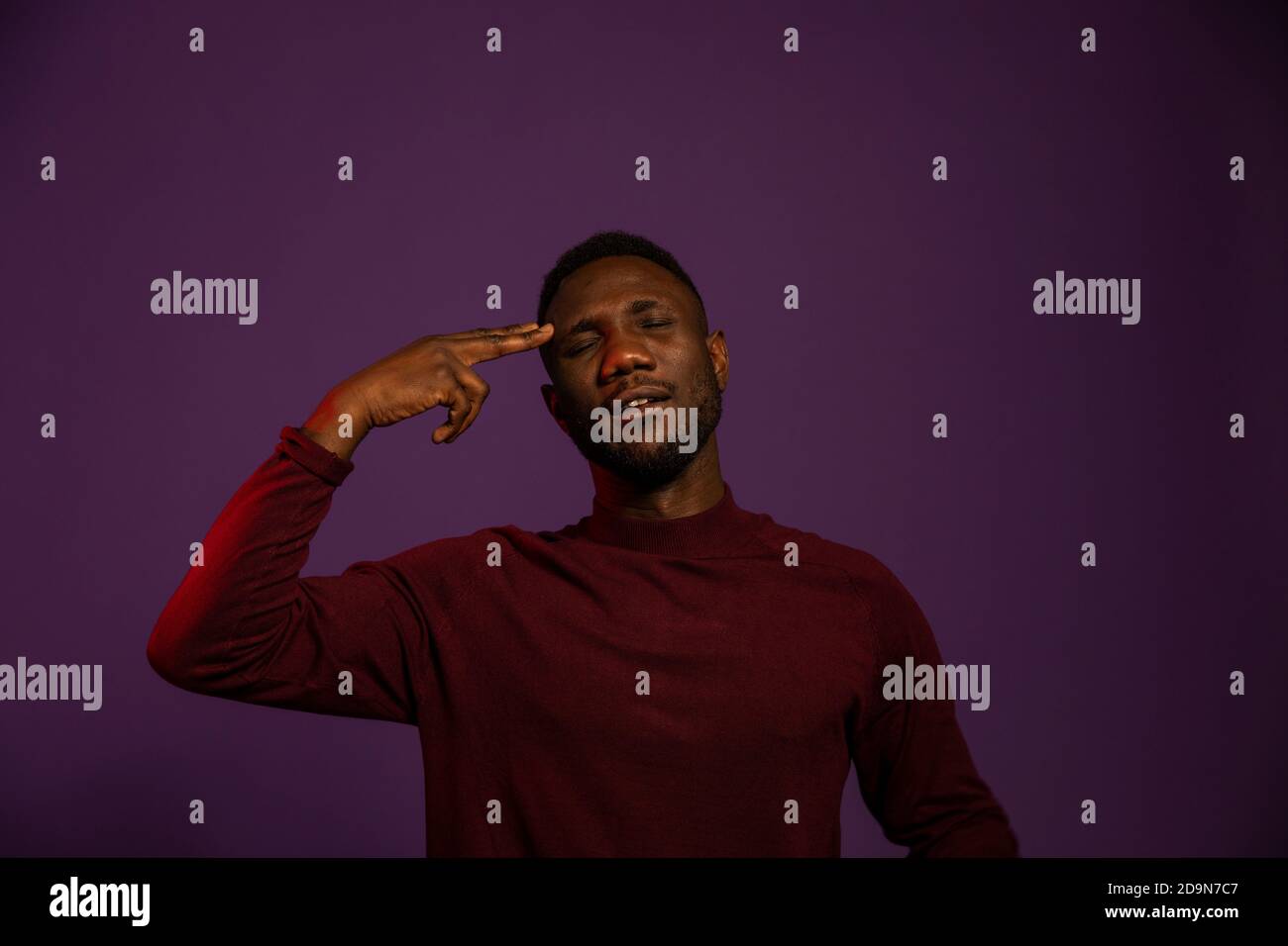 Young man showing shoot me gesture and body language. Fingers on temple ...