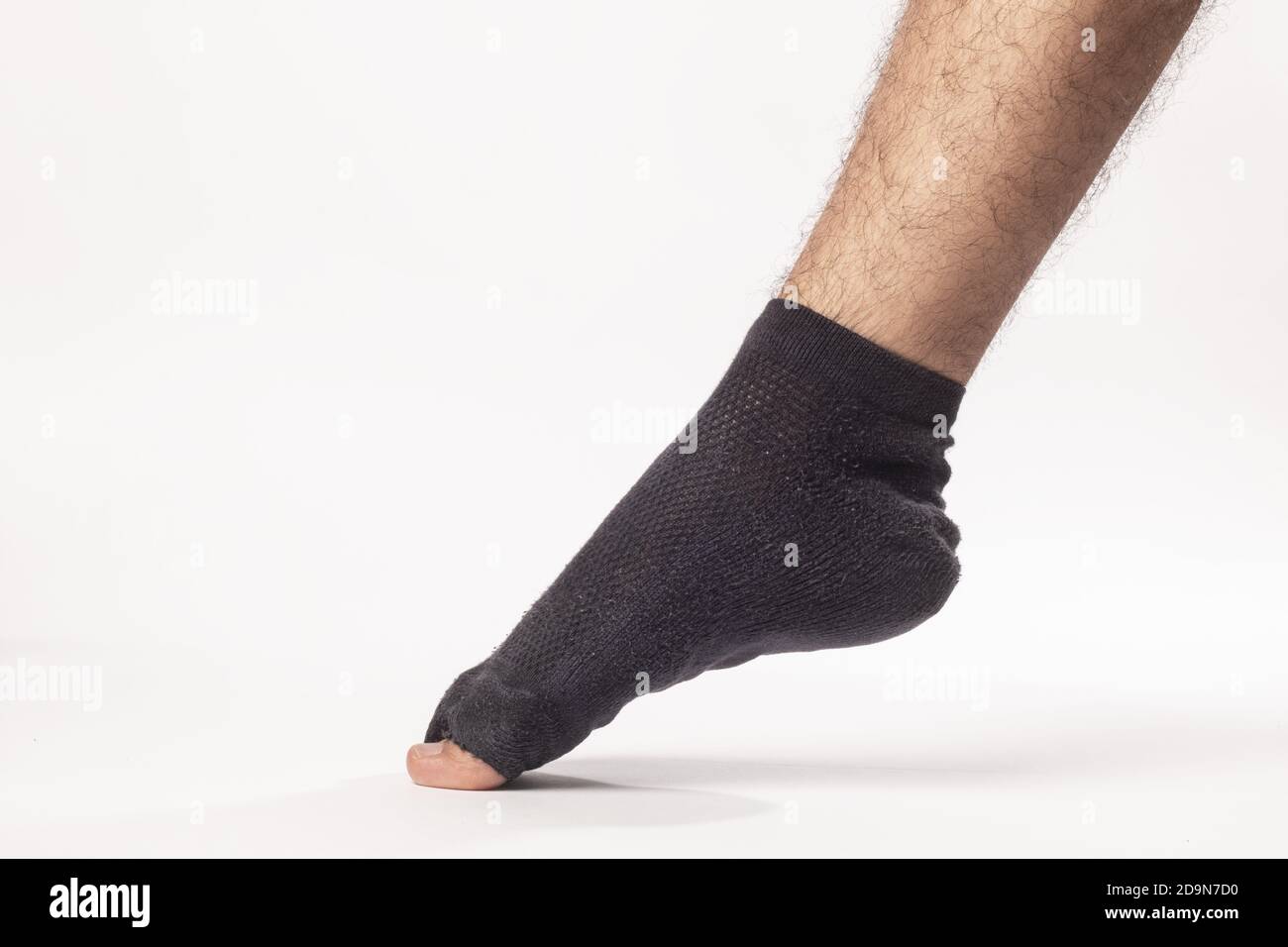 Closeup of the leg of a male wearing a sock with a hole isolated on a ...