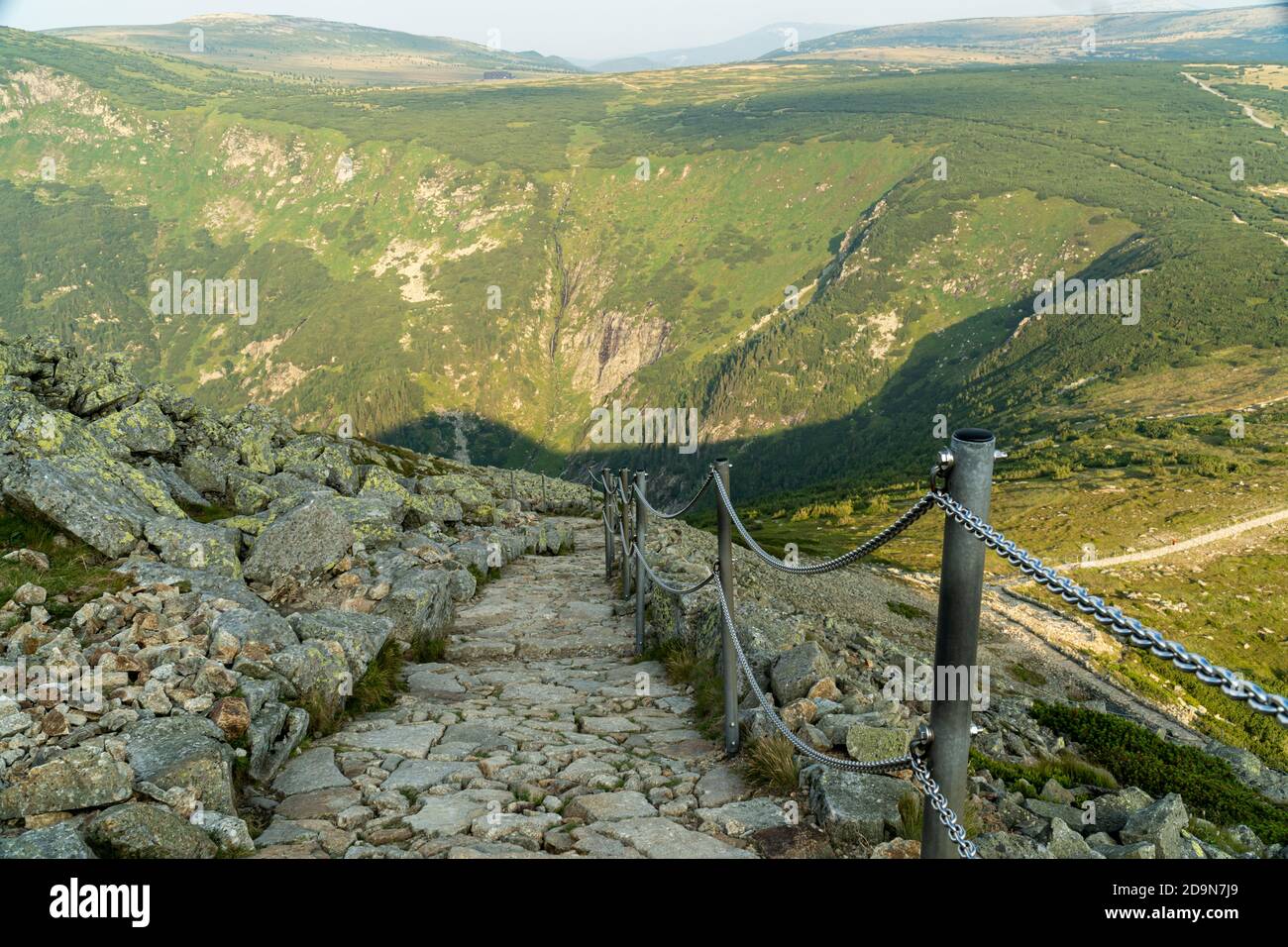 A steep mountain trail with handrails on chains, bright mountains in ...