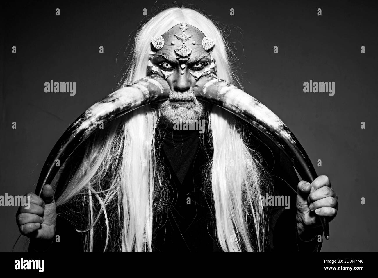 Elderly man holding two red horns. Demon head isolated on black ...