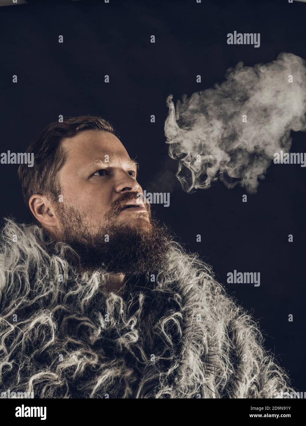 Solid bearded man dressed in a fur mantle exhaling vapour from his ...