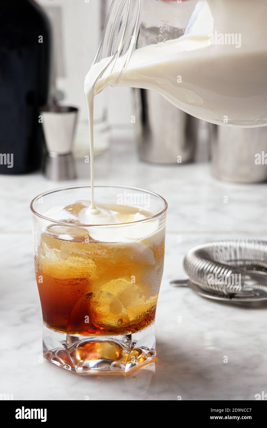 White Russian cocktail preparation. Pouring cream into the glass Stock ...