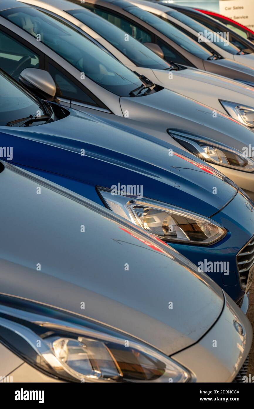 a row or line of new cars on display outside of a car dealership on the ...