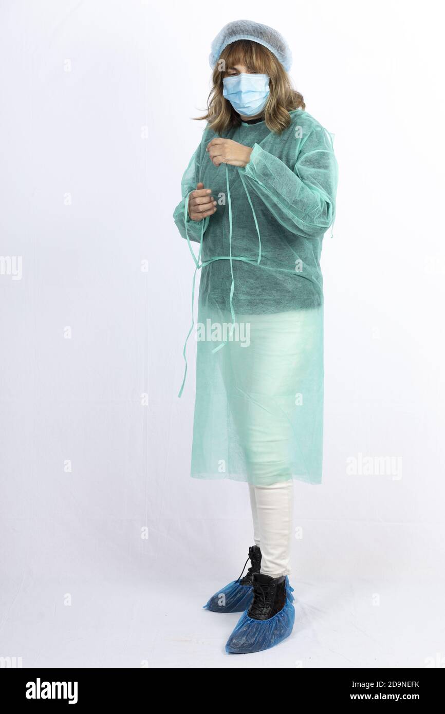 Middle-aged female wearing surgical gown, face mask, cap and shoe ...
