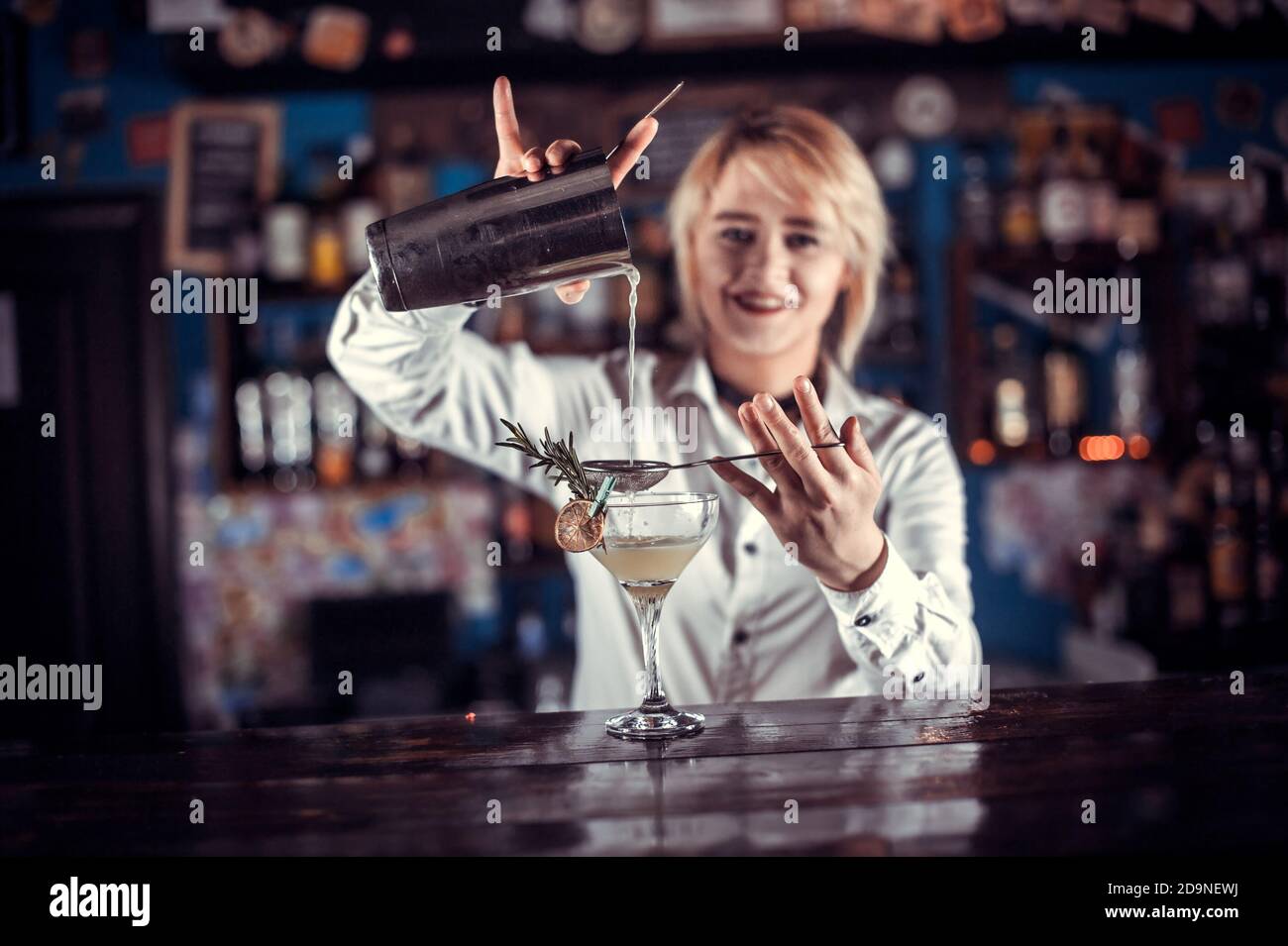 Charming barmaid places the finishing touches on a drink in the night ...