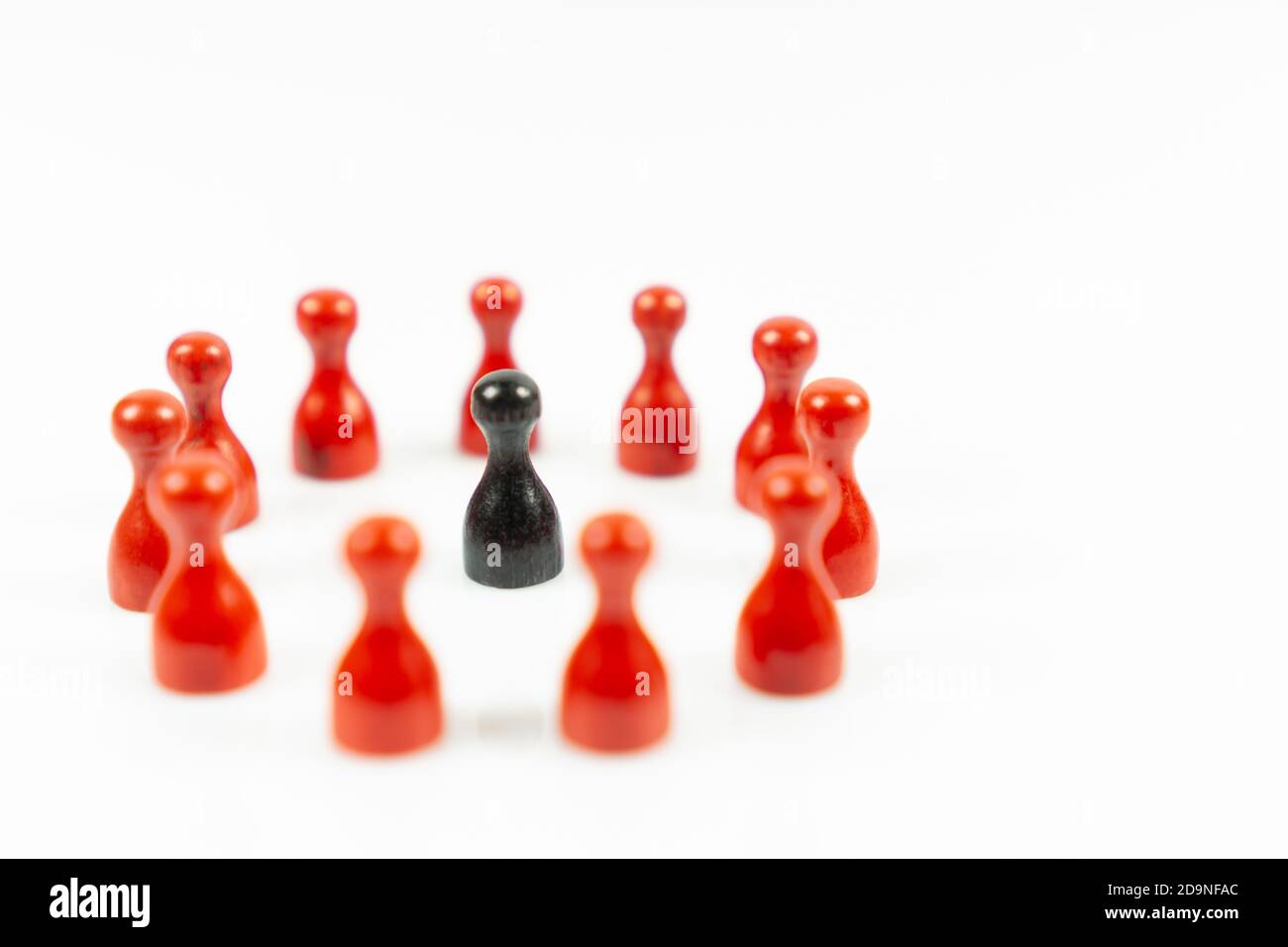 Red meeples in a circle and one black one in the middle Stock Photo - Alamy