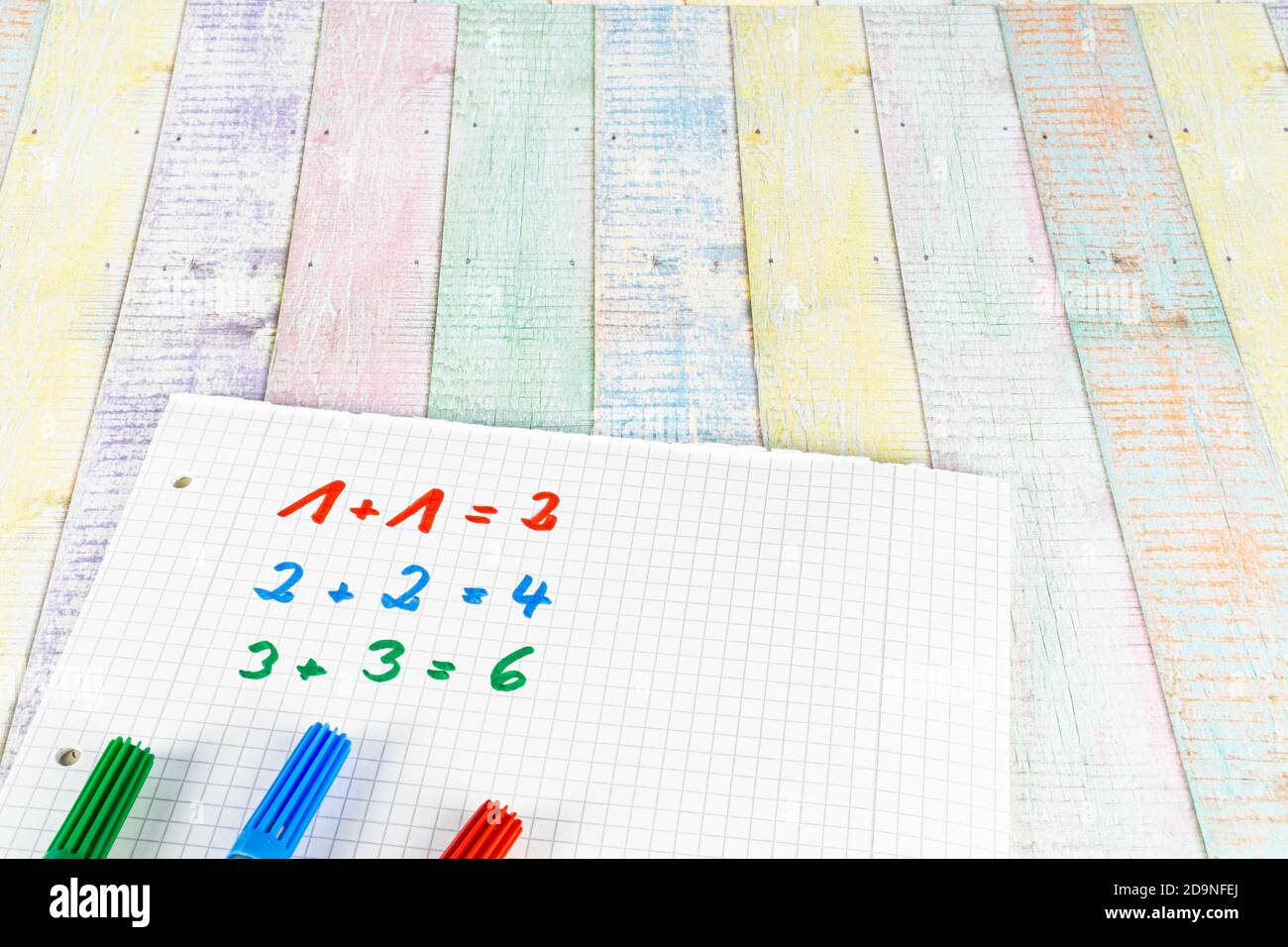 Block with simple calculating tasks on a colorful wooden background ...