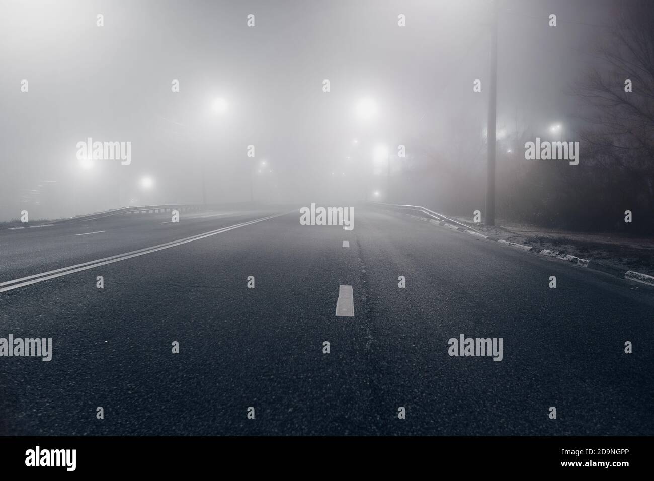 Foggy misty night road illuminated by street lights Stock Photo - Alamy