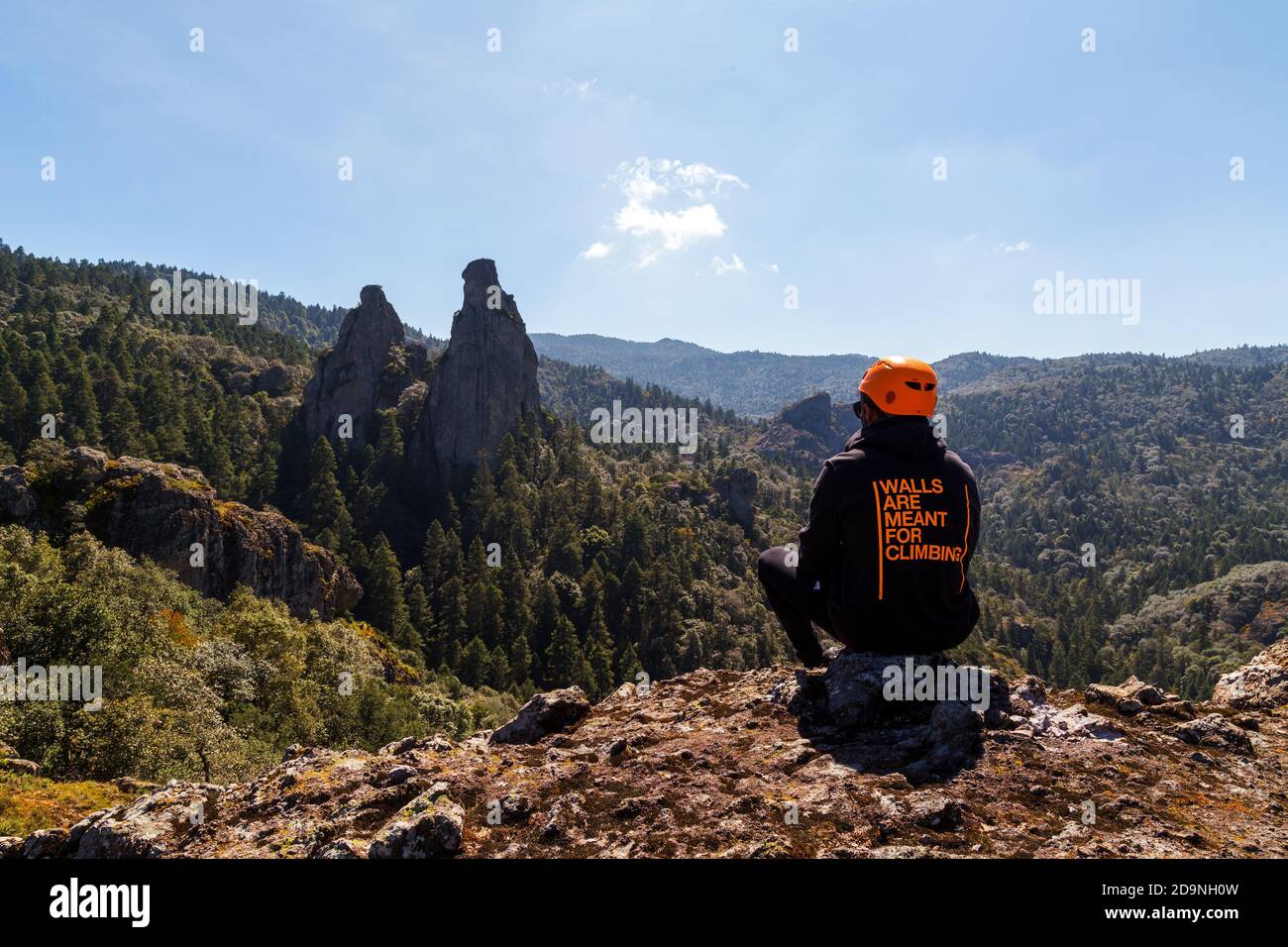 Closeup shot of a male rock climber sitting on the top of the mountain ...