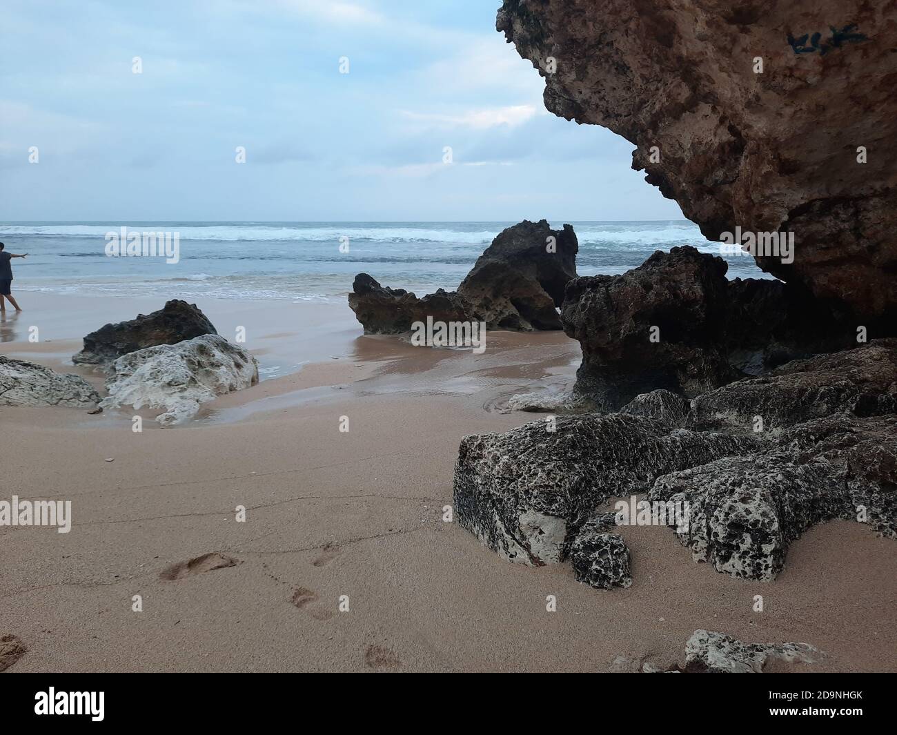 Single rocks on a sand beach against blue ocean and cloud sky at ...