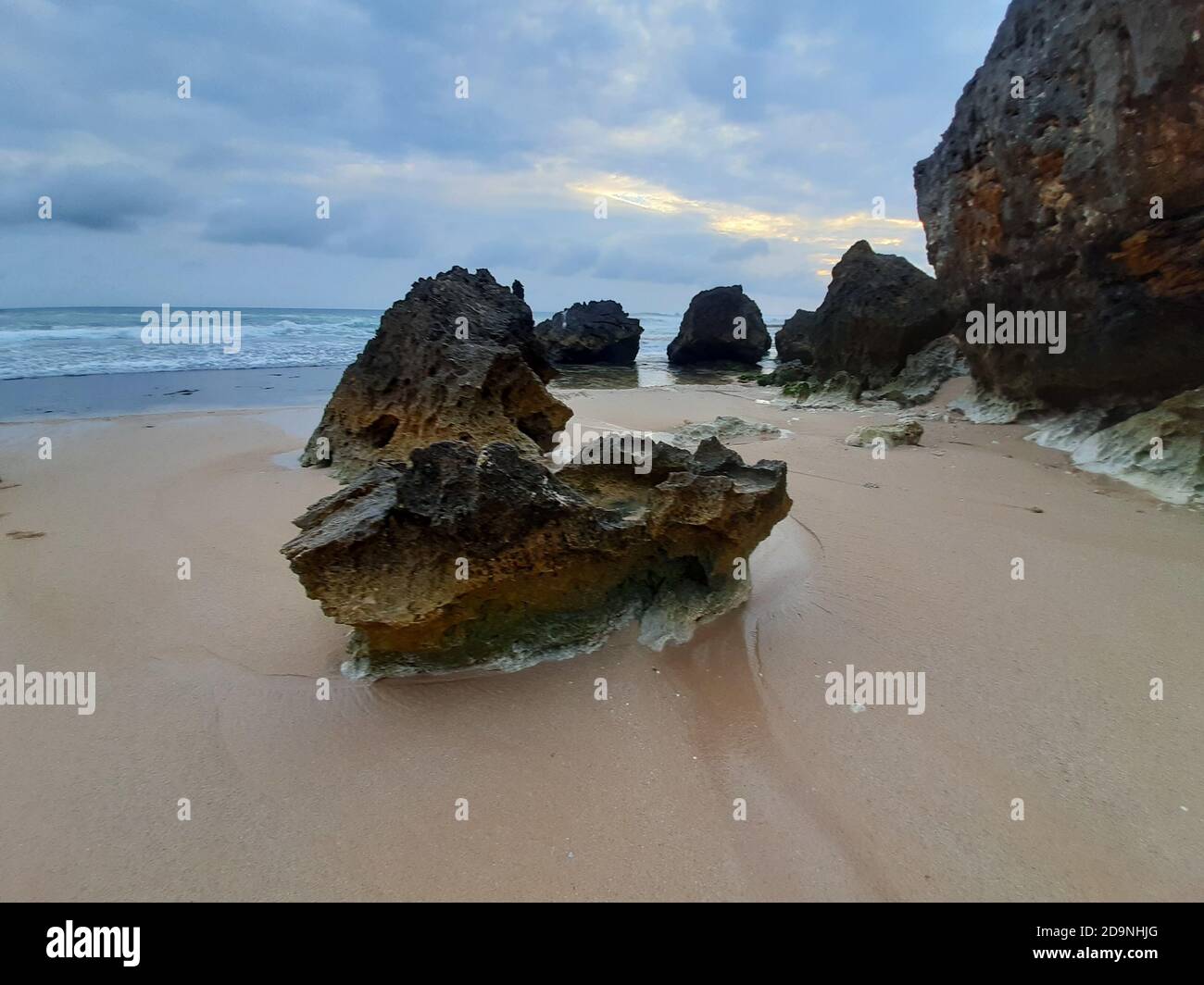 Single rocks on a sand beach against blue ocean and cloud sky at ...