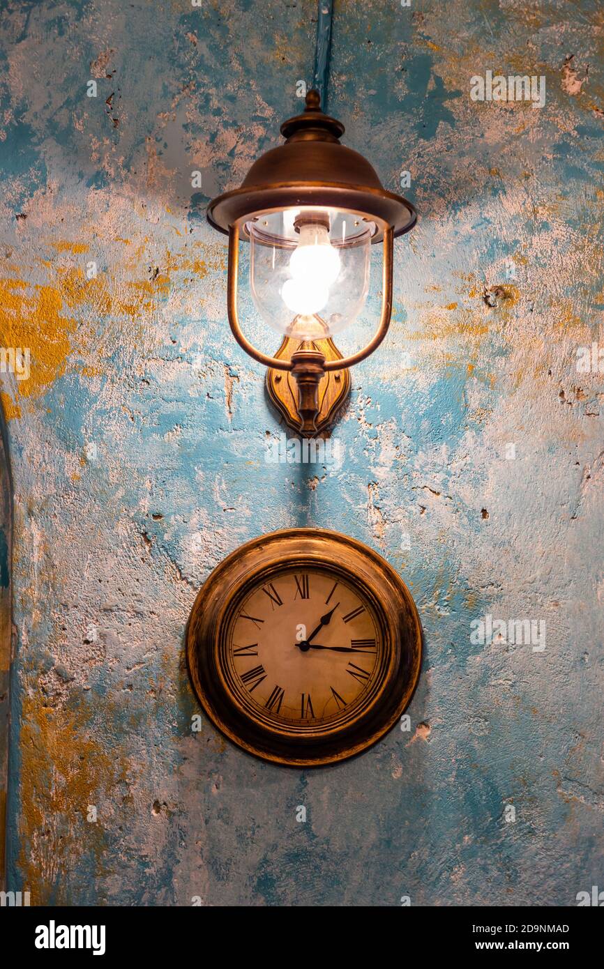 Ancient clock with antique lamp on an old cement wall background ...