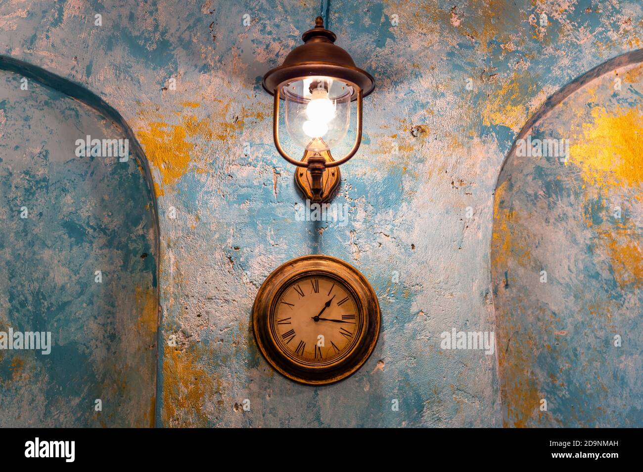 Ancient clock with antique lamp on an old cement wall background ...